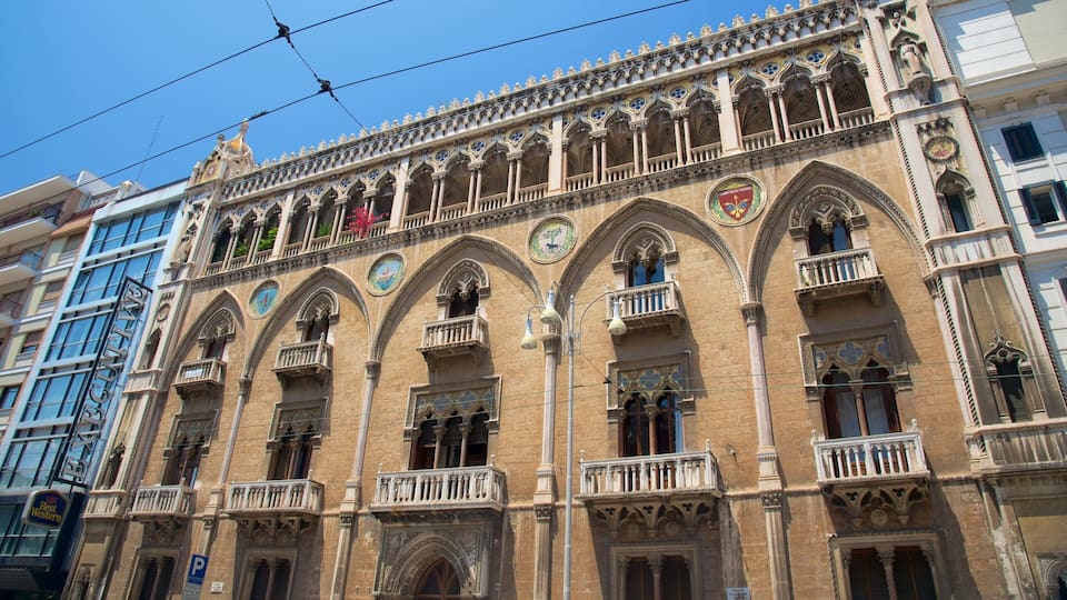 Um edifício histórico com arquitetura gótica ornamentada, apresentando arcos ogivais, esculturas detalhadas em pedra e uma série de varandas.