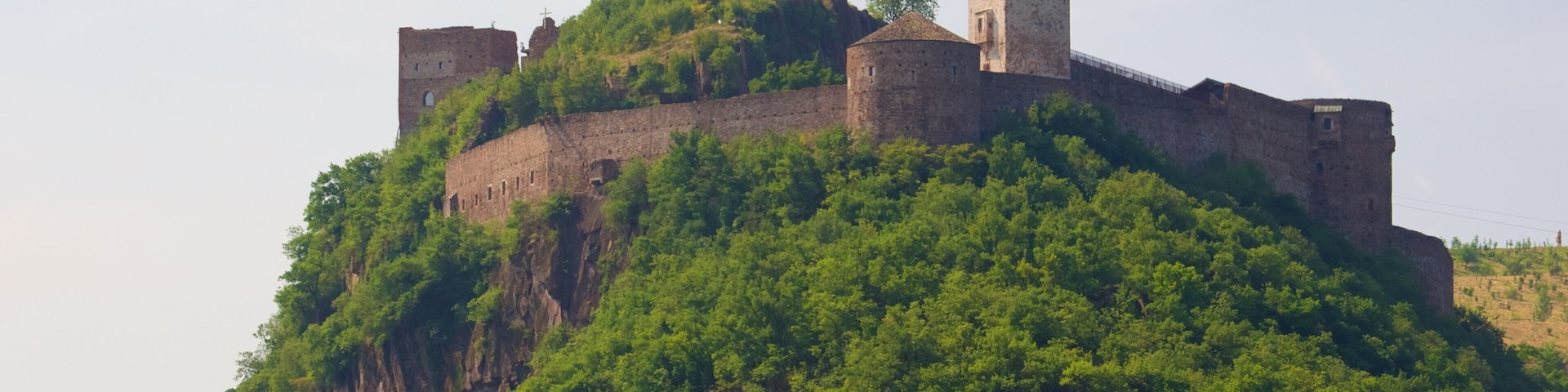 Castelo Firmiano caracterizando montanhas e um pequeno castelo ou palácio