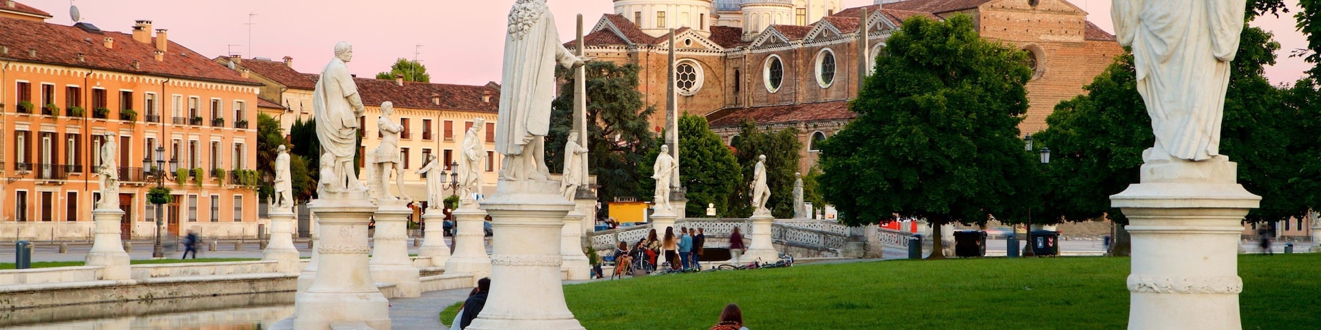 Uma fonte histórica com estátuas, um rio e uma igreja com cúpulas ao fundo.