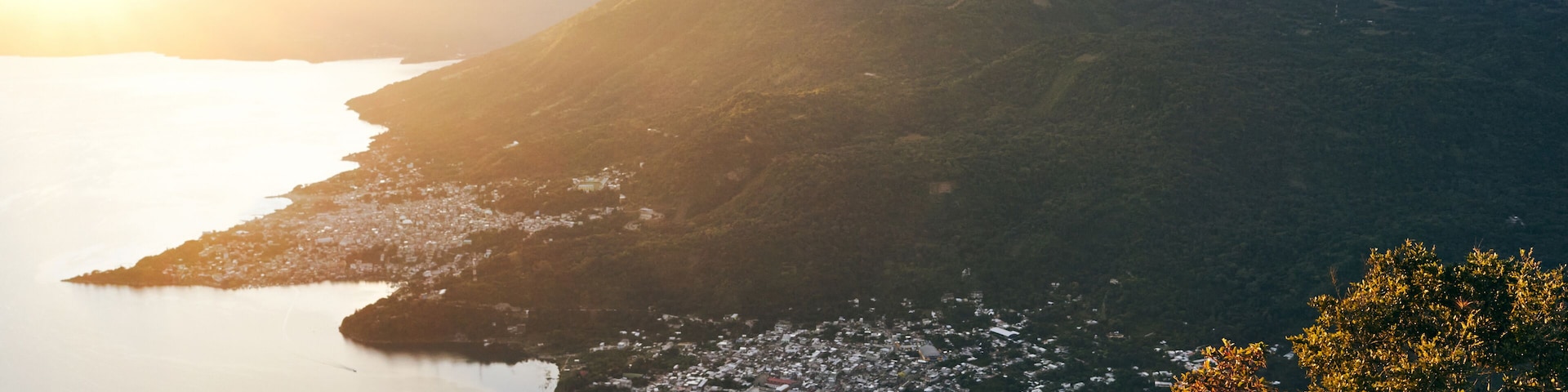 Paisagem montanhosa com um corpo d'água e uma cidade abaixo.