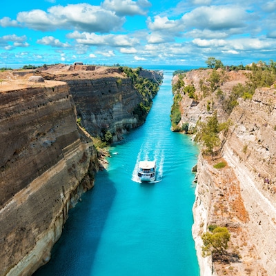 Um cânion fluvial com um barco no meio, cercado por penhascos e vegetação rasteira.