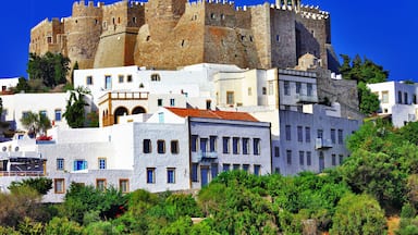 Um castelo histórico no alto de uma colina, com edifícios brancos em primeiro plano.