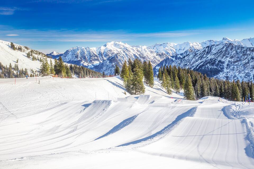 Pista de esqui coberta de neve com montanhas ao fundo.