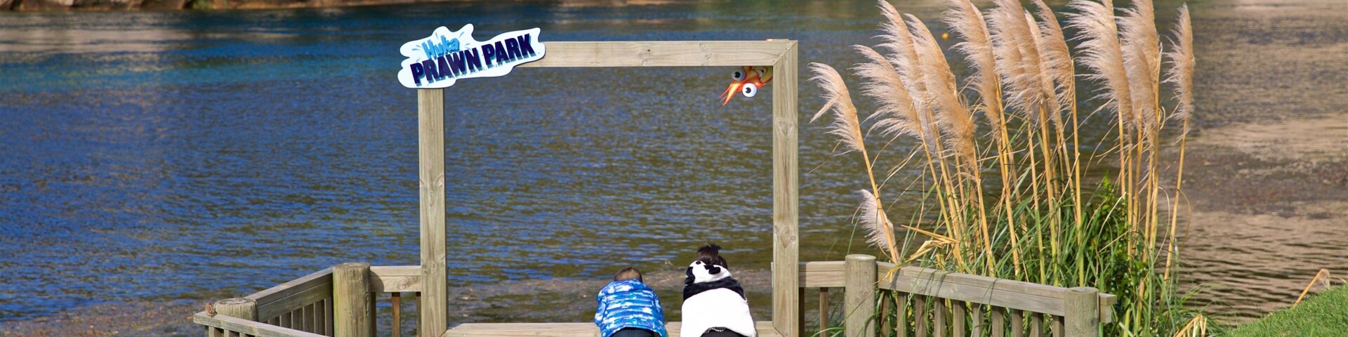 Prawn Farm showing a river or creek and signage as well as a family