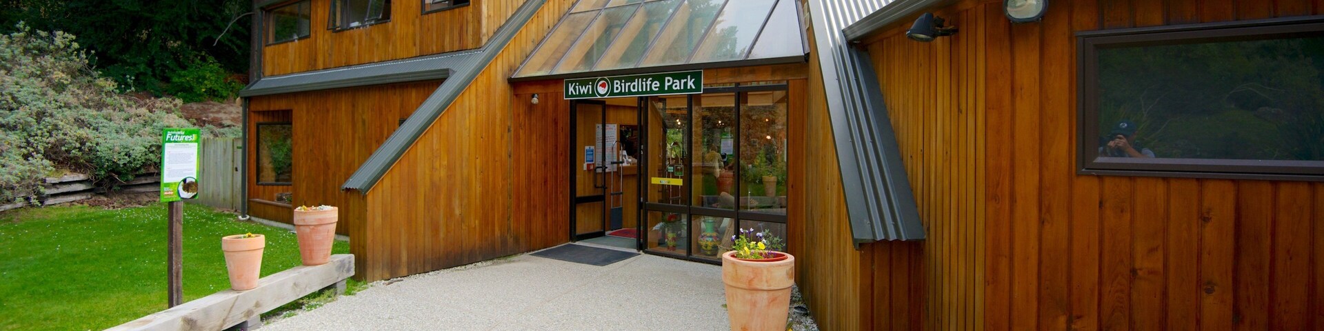Um edifício de madeira com uma placa que diz 'Kiwi Birdlife Park' e um caminho de cascalho que leva até ele.