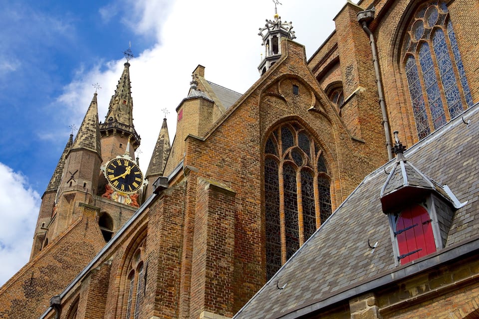 Uma igreja histórica com uma torre de relógio grande e detalhes de tijolos elaborados.