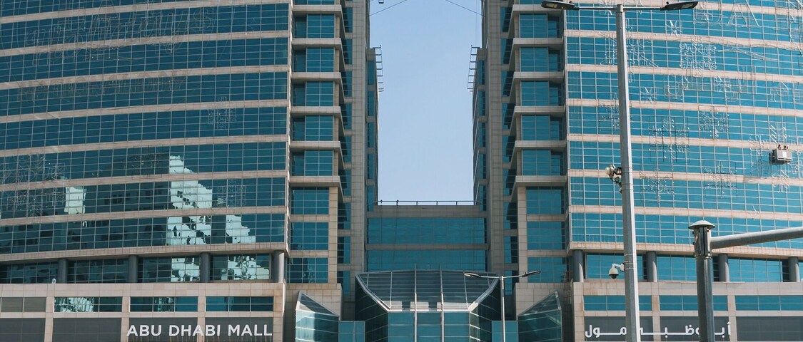 Um edifício moderno com uma entrada central imponente e a placa do Abu Dhabi Mall.