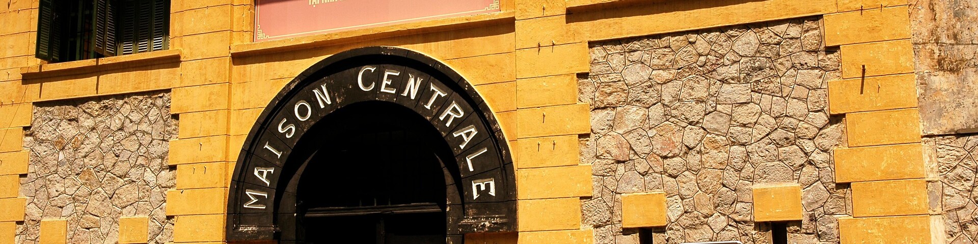 Um edifício histórico com fachada de pedra e um arco preto com a inscrição 'MAISON CENTRALE'.