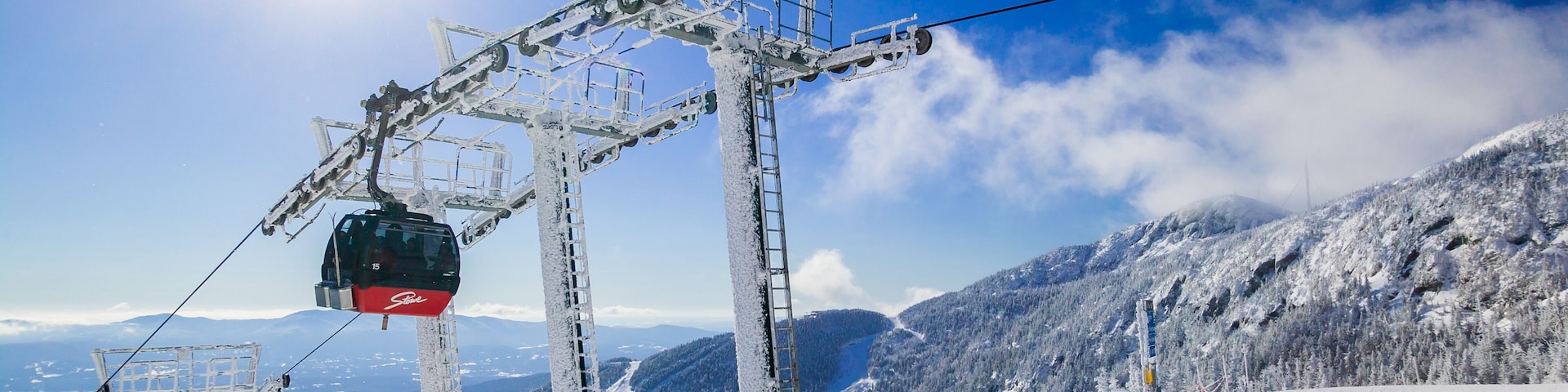 Um teleférico com gôndola, montanhas cobertas de neve e um céu azul claro.