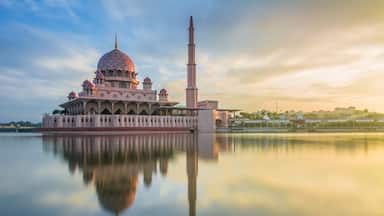 Uma mesquita com uma cúpula grande e minaretes, refletindo em águas calmas.