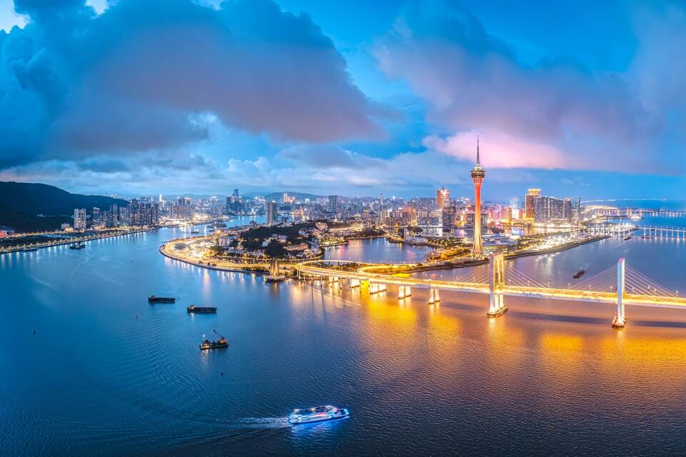 Paisagem urbana com uma torre imponente, uma grande massa d'água e uma ponte.
