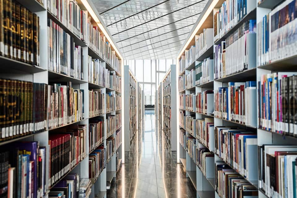 Uma biblioteca com estantes de livros em ambos os lados e teto de vidro.