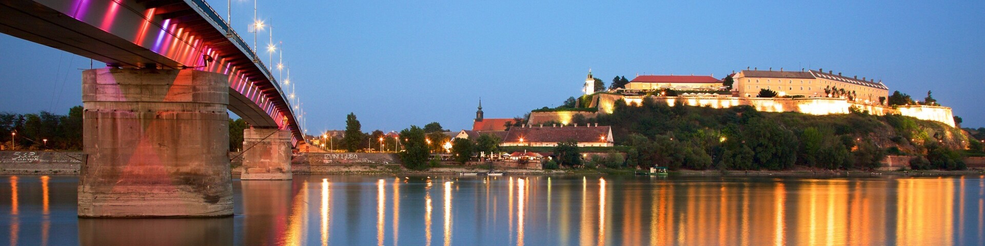 Petrovaradin Fortress showing a river or creek, night scenes and a bridge