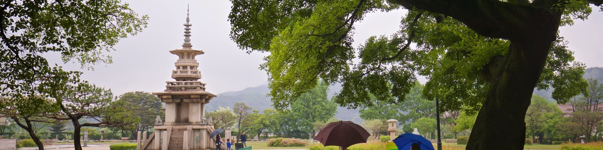 Um pagode num parque, com pessoas caminhando sob árvores.