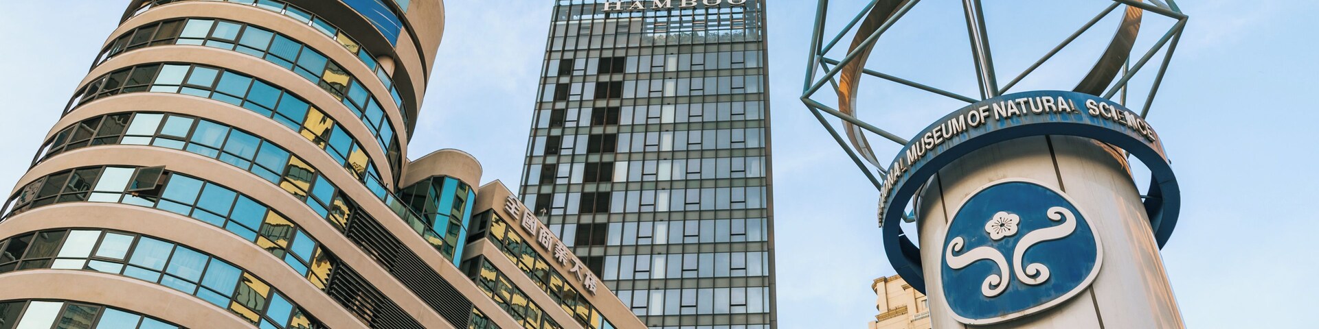 Um edifício moderno com fachada curva e um grande letreiro com caracteres chineses.