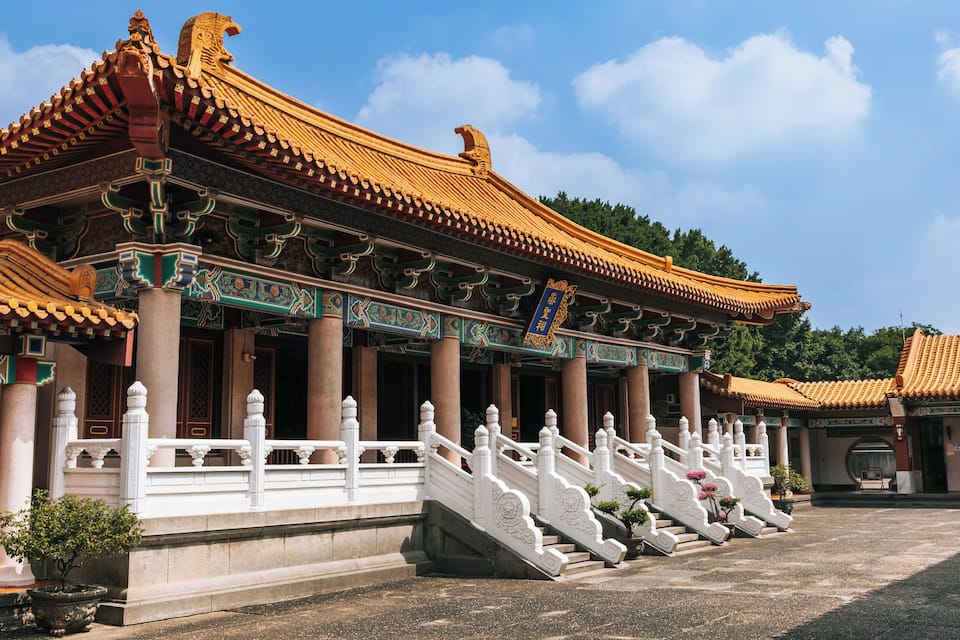 Um edifício tradicional chinês com telhados ornamentados em amarelo e decorações verdes.