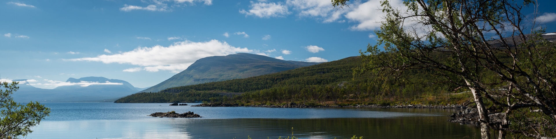 Um lago rodeado por montanhas e vegetação exuberante.
