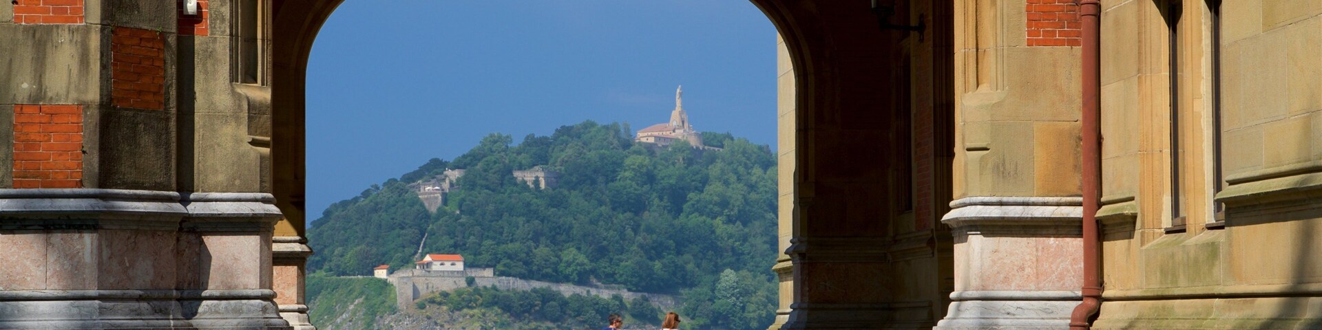 Arcada que leva a um topo de colina com uma estátua.