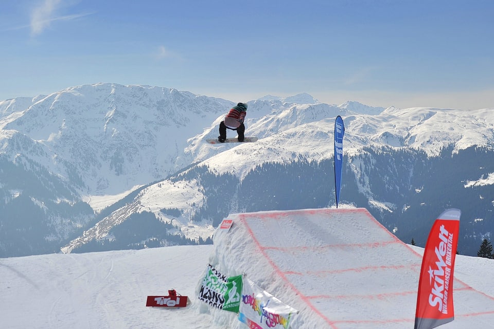 Um snowboarder numa encosta nevada de montanha sob um céu limpo.