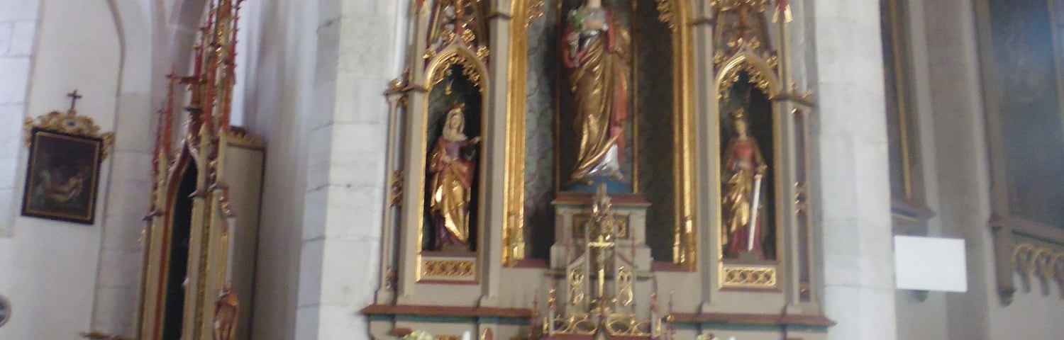 Um altar de igreja ornamentado com estátuas religiosas e uma grande cruz.
