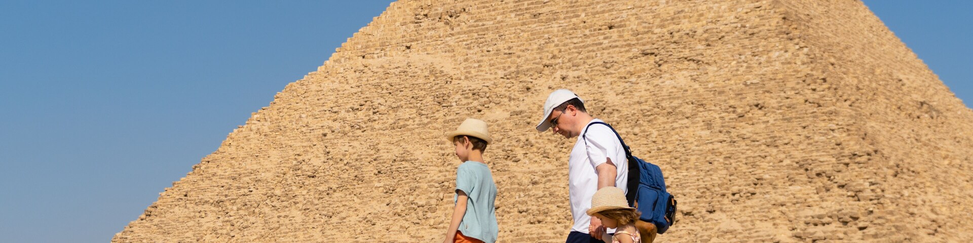 Uma pirâmide imponente com turistas caminhando ao redor.