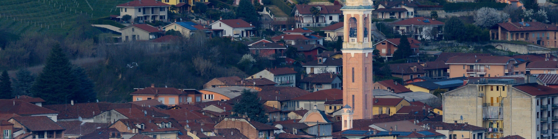Uma cidade com uma torre do relógio imponente, vinhedos em socalcos e casas densamente aglomeradas.