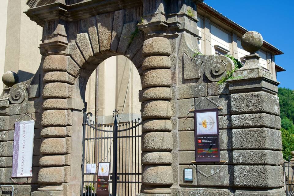 Um arco de pedra ornamentado com um portão de metal, bandeiras e uma placa.