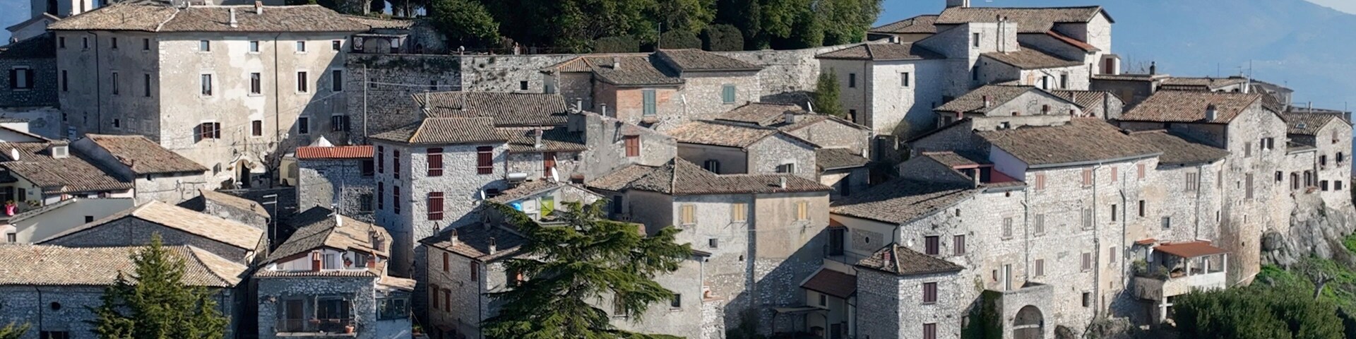 Uma cidade histórica com edifícios de pedra e montanhas ao fundo.