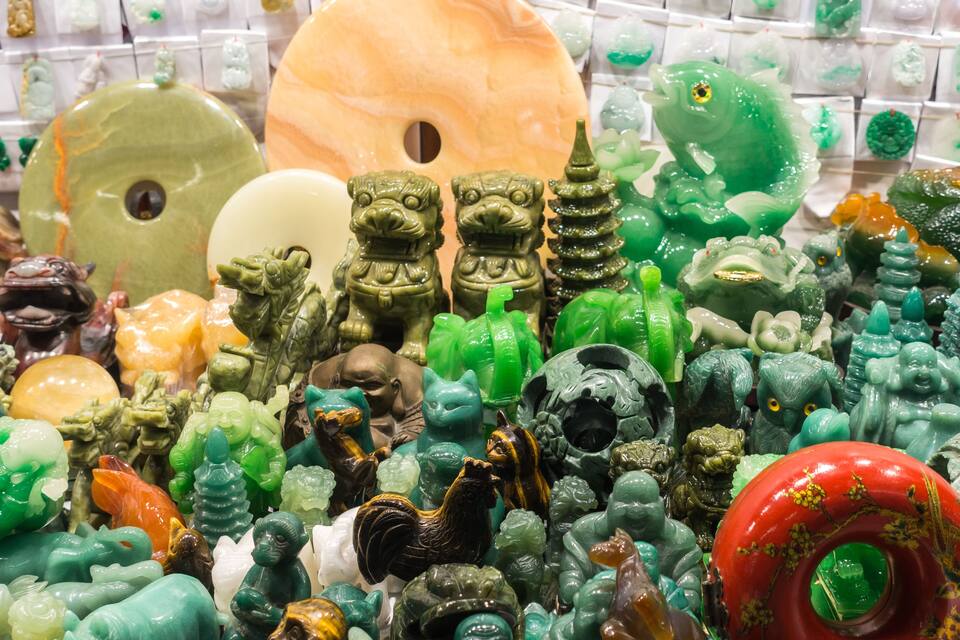 Exposição de esculturas em jade, incluindo diversos animais e figuras, em uma loja.
