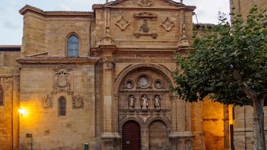 Uma igreja histórica com uma grande entrada em arco, estátuas e uma cruz no telhado.