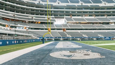 Um estádio vazio com um campo de futebol e uma grande placa com a inscrição 'Cowboys Stadium'.