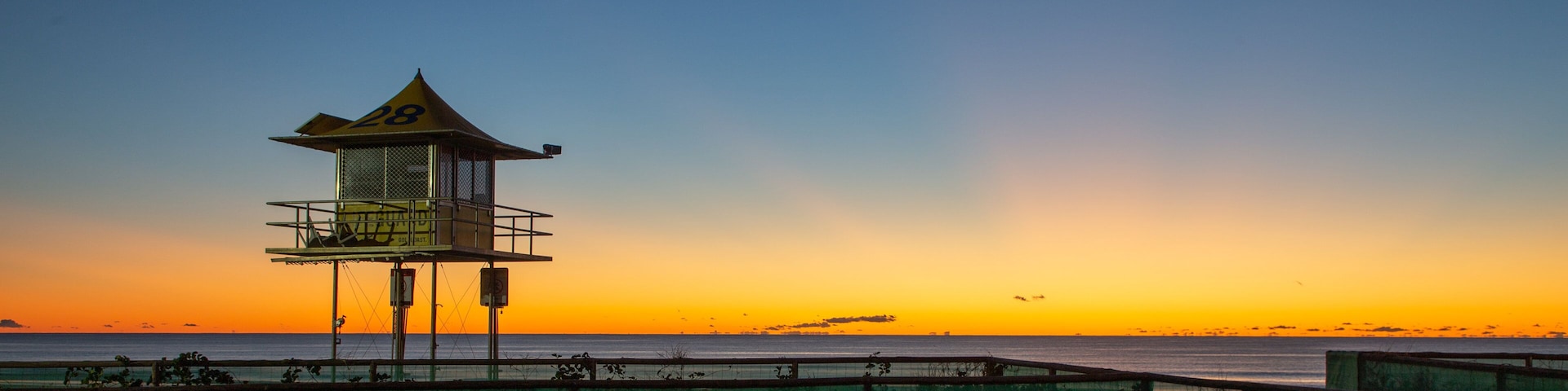 Uma torre de salva-vidas ao pôr do sol, à beira-mar.