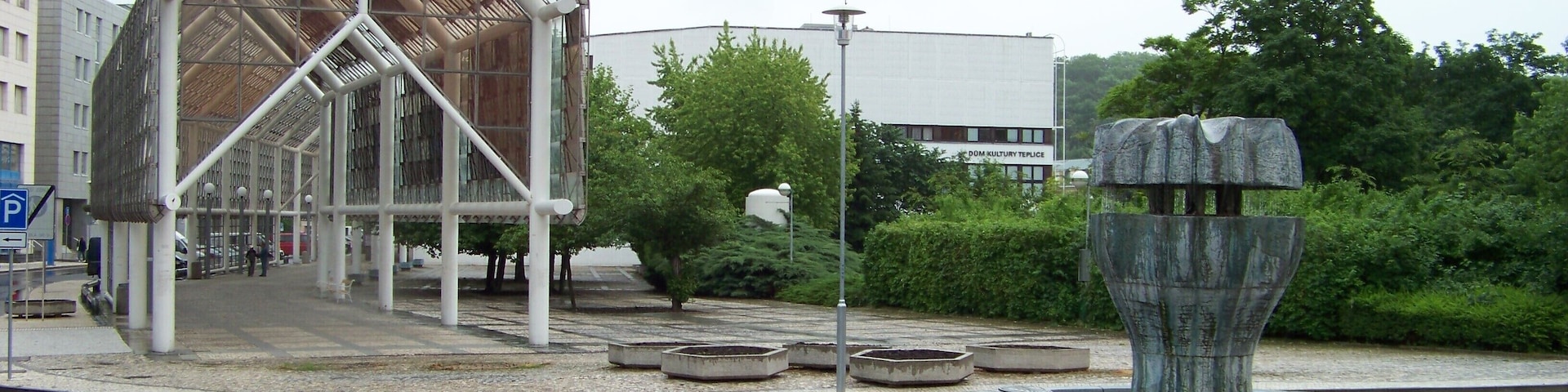 Um edifício moderno com telhado triangular, uma fonte e calçada de pedra.
