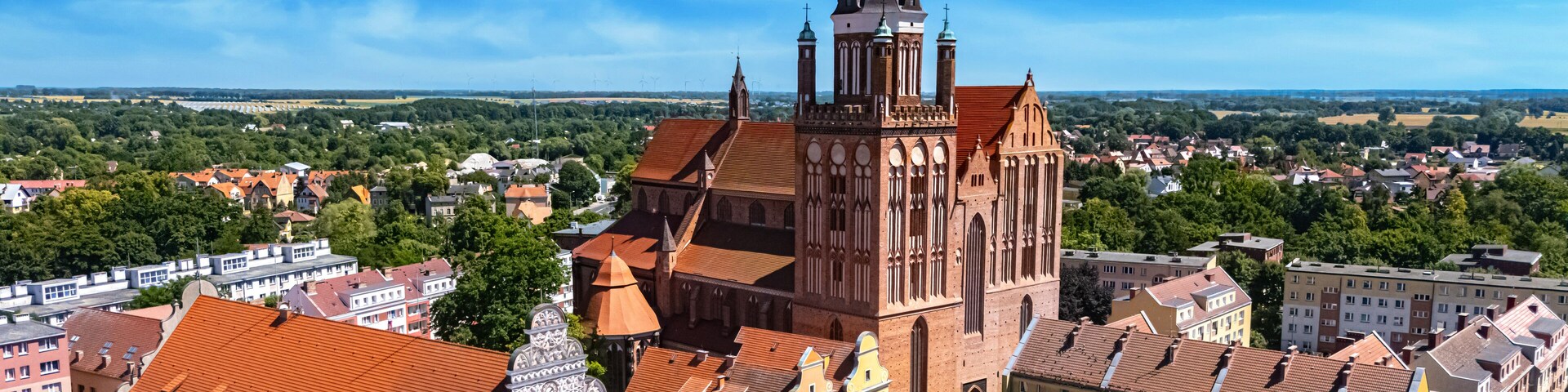 Uma igreja histórica com uma torre alta, rodeada por edifícios coloridos e um céu azul claro.