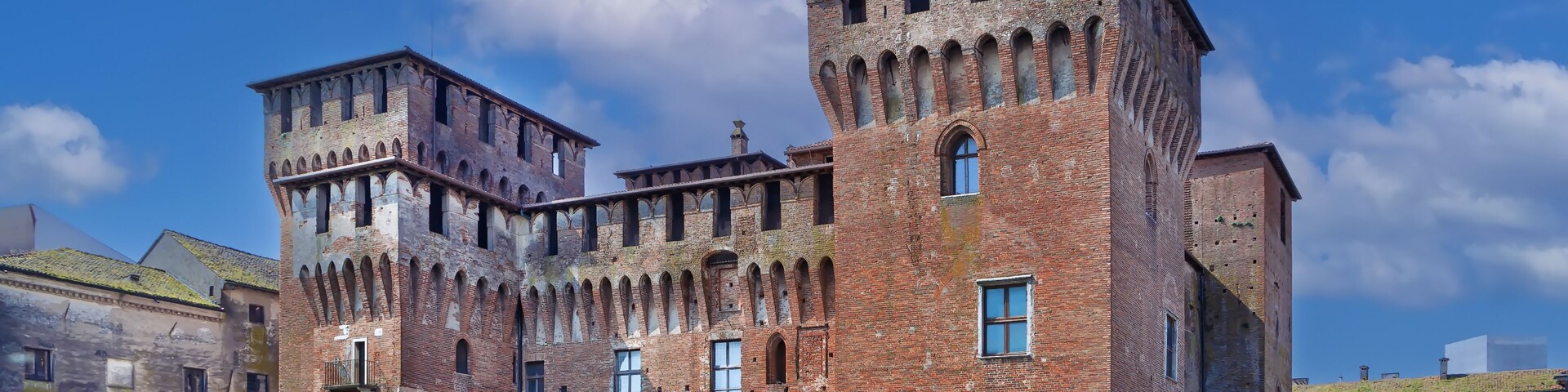 Um edifício histórico de tijolos com janelas em arco e uma torre.