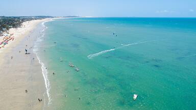 Uma praia com águas turquesa cristalinas, areal arenoso e vários barcos.