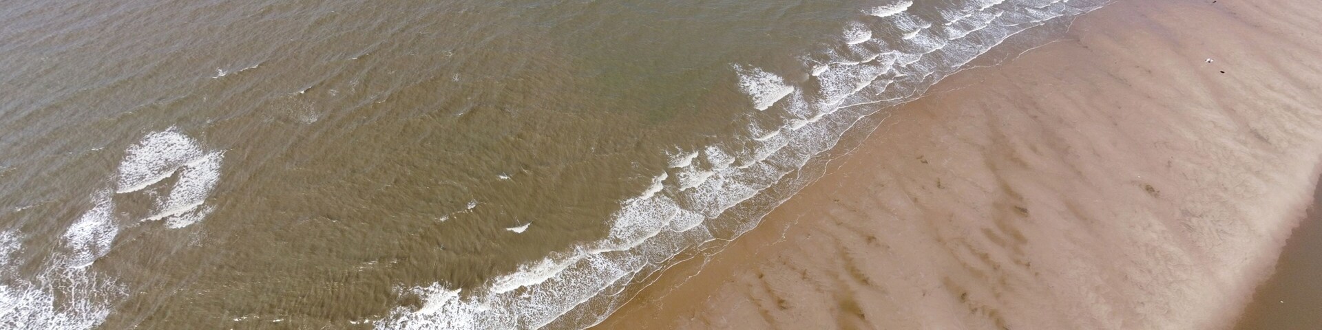 Uma praia arenosa com ondas suaves batendo na costa.