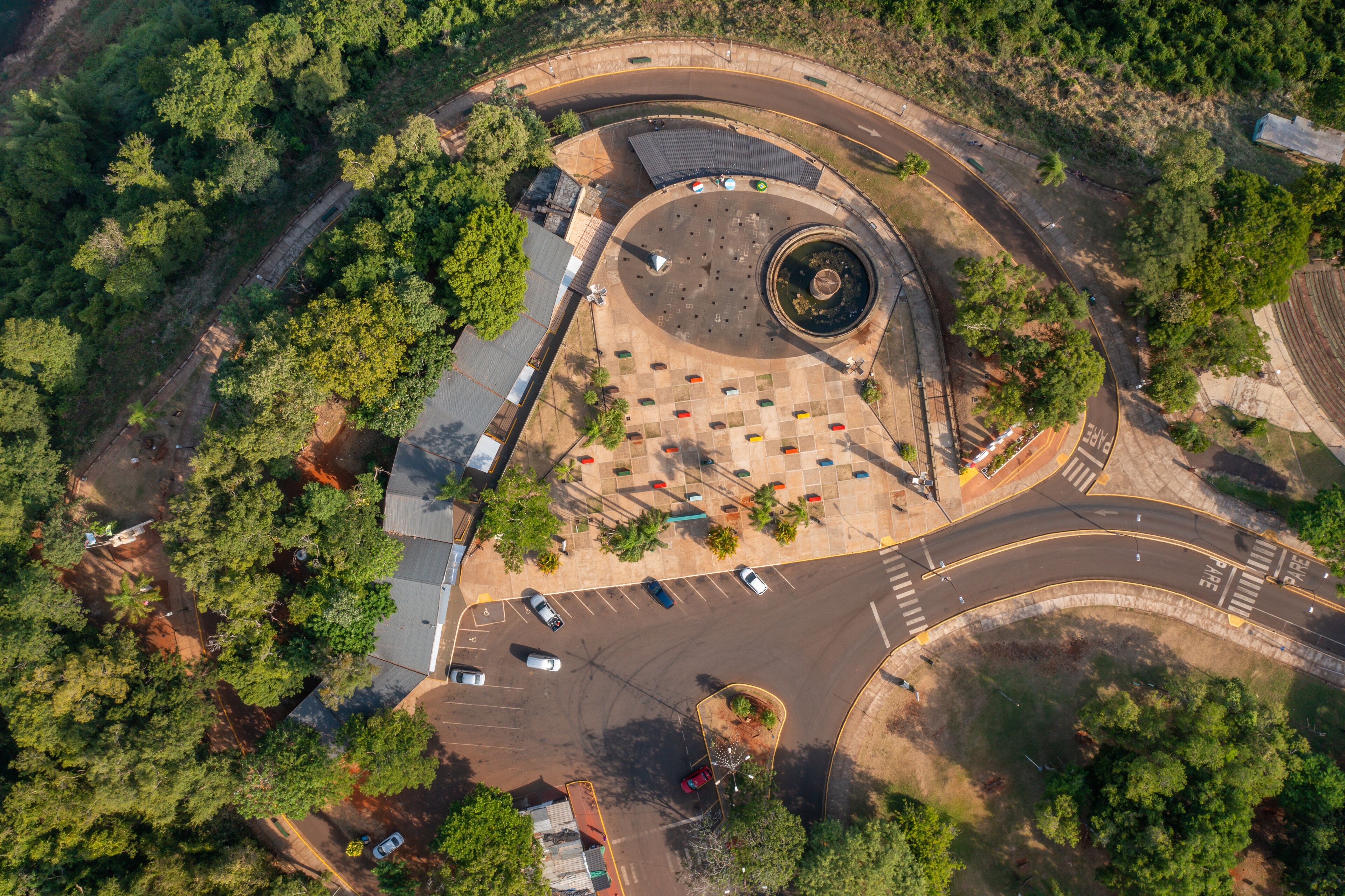 Vista aérea de um jardim com um carrossel e carros estacionados.