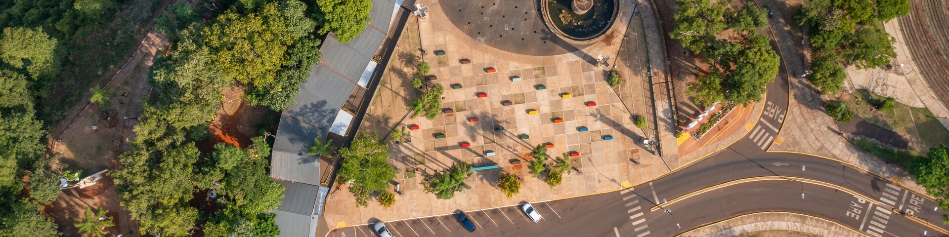 Vista aérea de um jardim com um carrossel e carros estacionados.