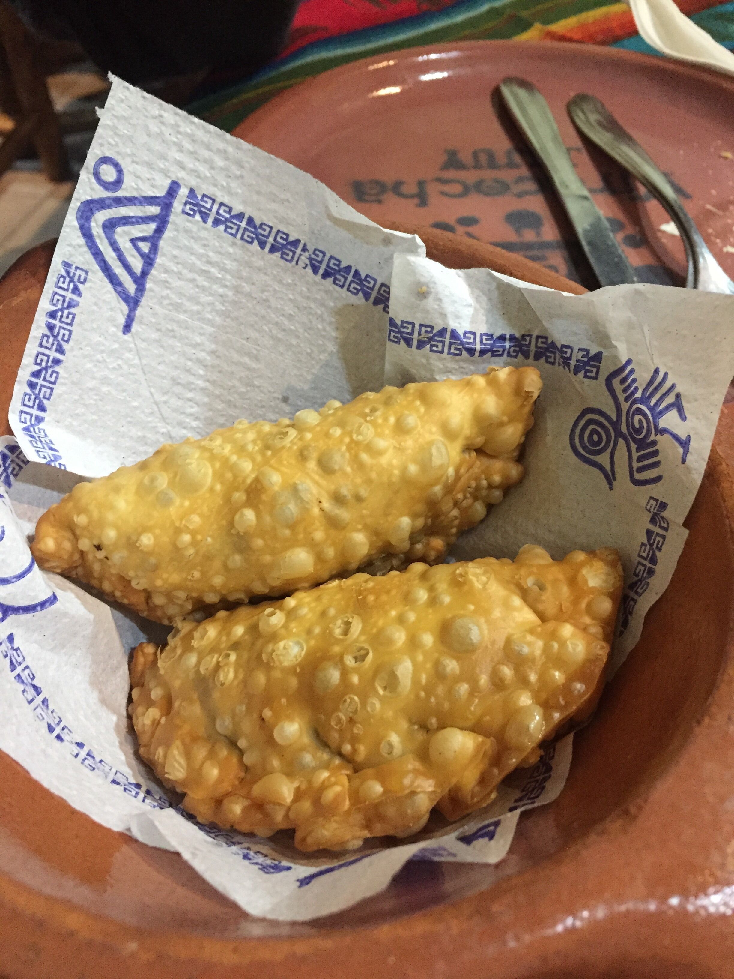 Duas iguarias fritas sobre papel com texto azul.