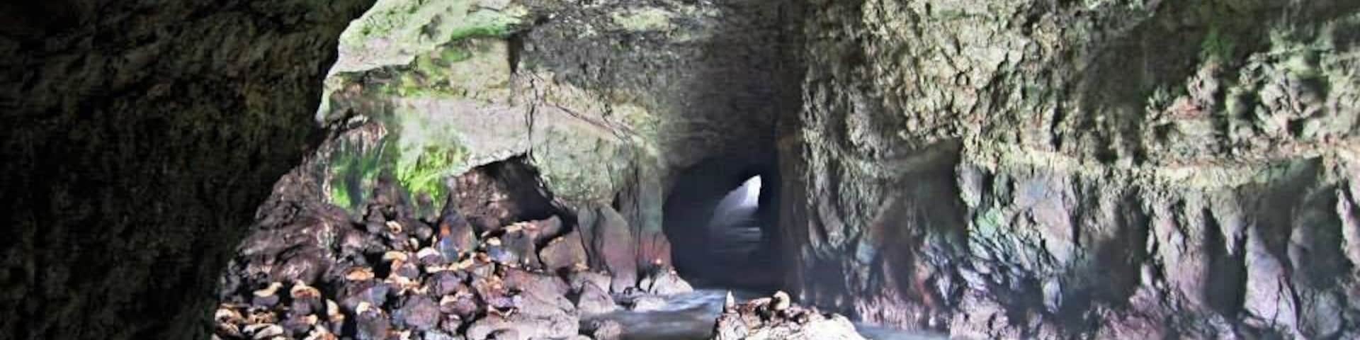 Caverna com interior rochoso e túnel que leva a um corpo d'água.
