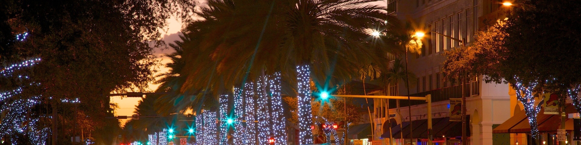 Miracle Mile at dusk showcases festive lights and bustling traffic in Coral Gables, Florida