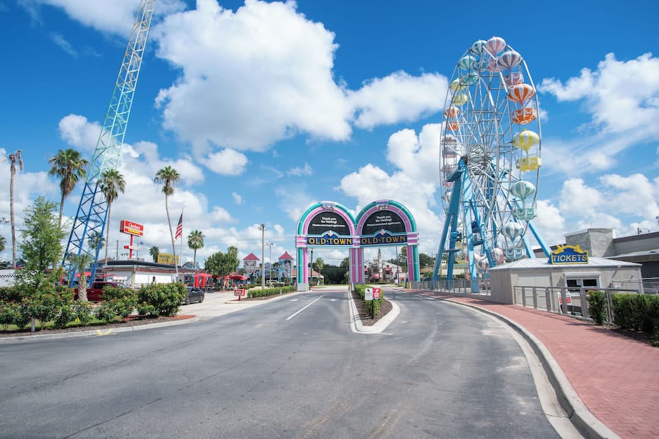 Entrada de parque temático com roda gigante e montanha-russa.