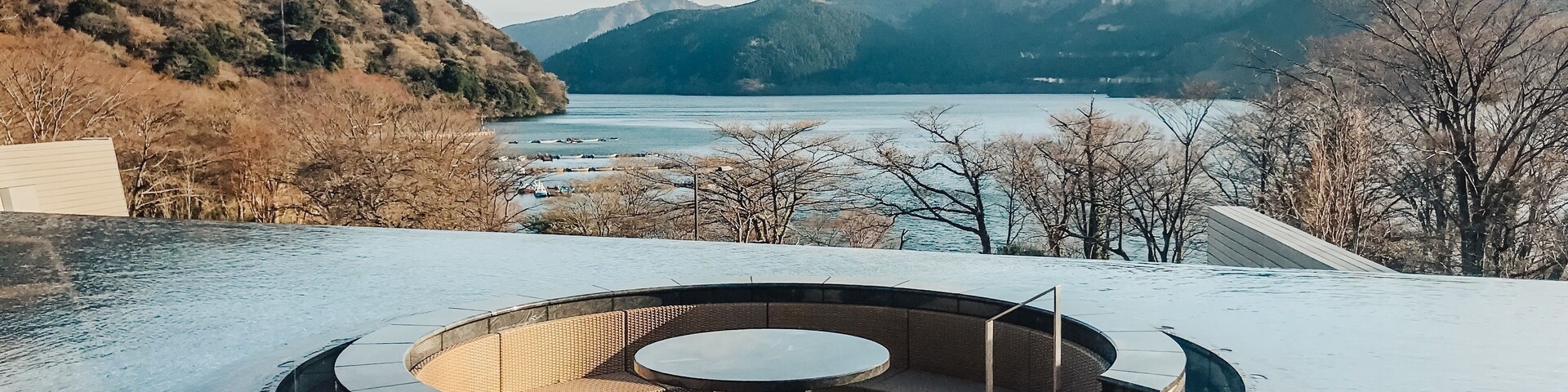 Uma piscina circular com vista para um lago e montanhas ao fundo.