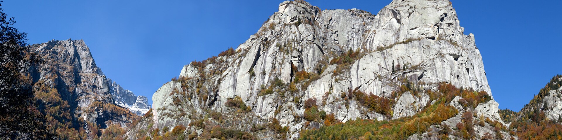 Montanha acidentada com penhascos íngremes e árvores em tons de outono.
