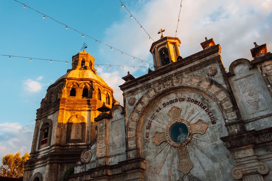 Um edifício histórico com arquitetura elaborada, incluindo uma cúpula e uma grande entrada em arco com inscrições.