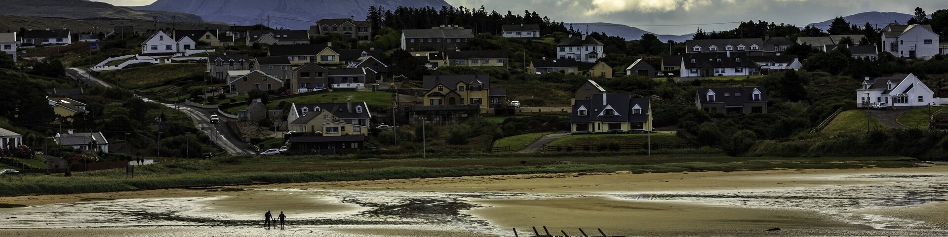 Bunbeg with Mount Errigal in the background and the wrecked Cara Na Mara (Friend of the Sea) on the tidal sand banks of Magheraclogher beach Donegal. 'Bád Eddie' (Eddie's Boat) ran ashore due to rough seas in the early 70s