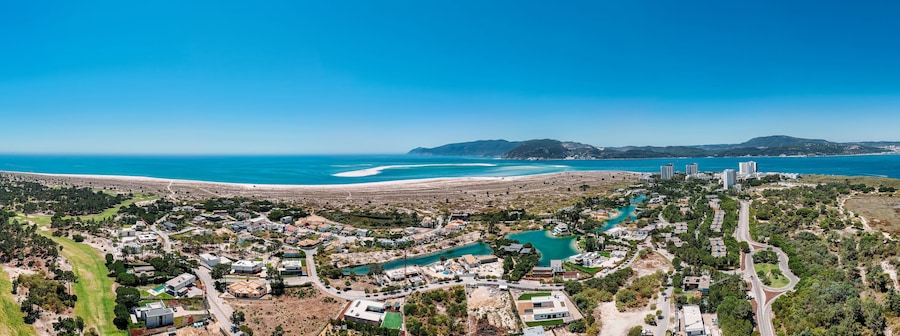 Uma cidade costeira com praia, águas azul-turquesa e uma mistura de edifícios residenciais e comerciais.