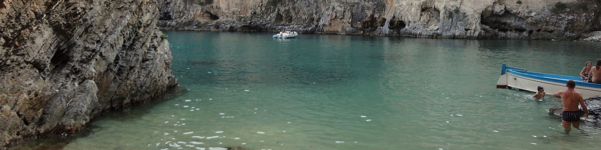 Um cânion rochoso com águas turquesa cristalinas e um barco perto da margem.