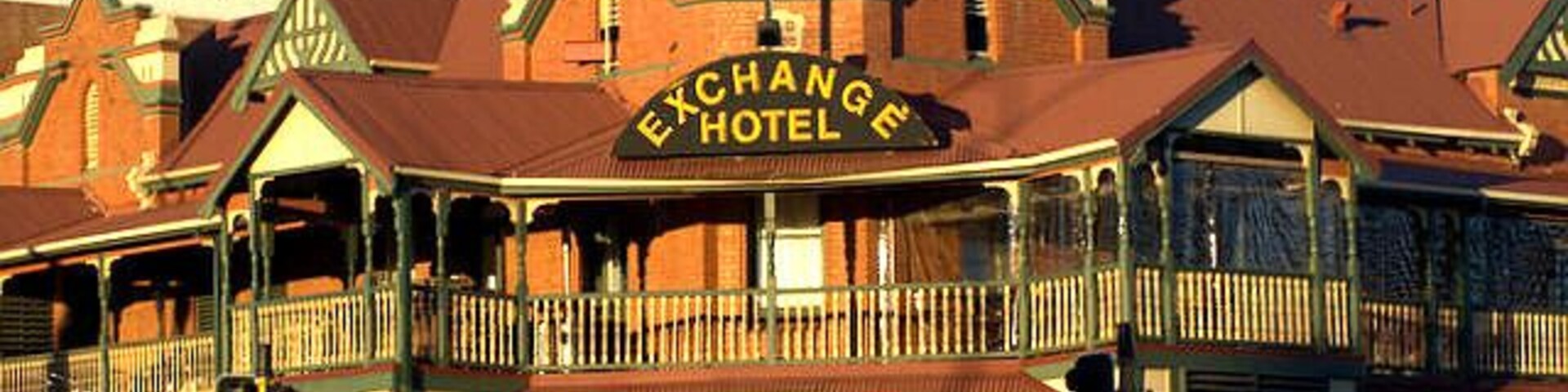 O Exchange Hotel, com uma placa visível, uma varanda e estilo arquitetônico tradicional.